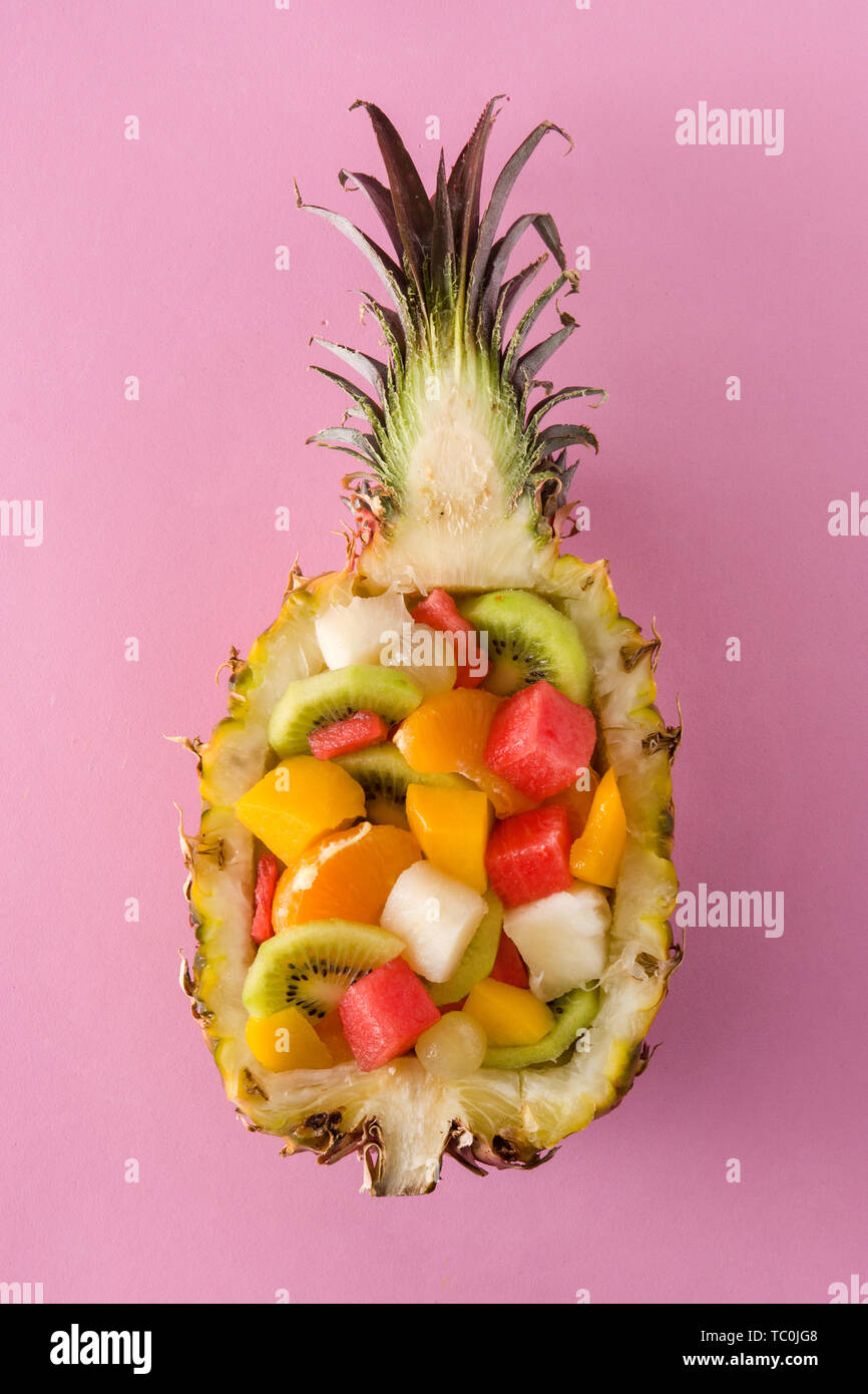 Mix fruit served inside pineapple on pink background Stock Photo - Alamy