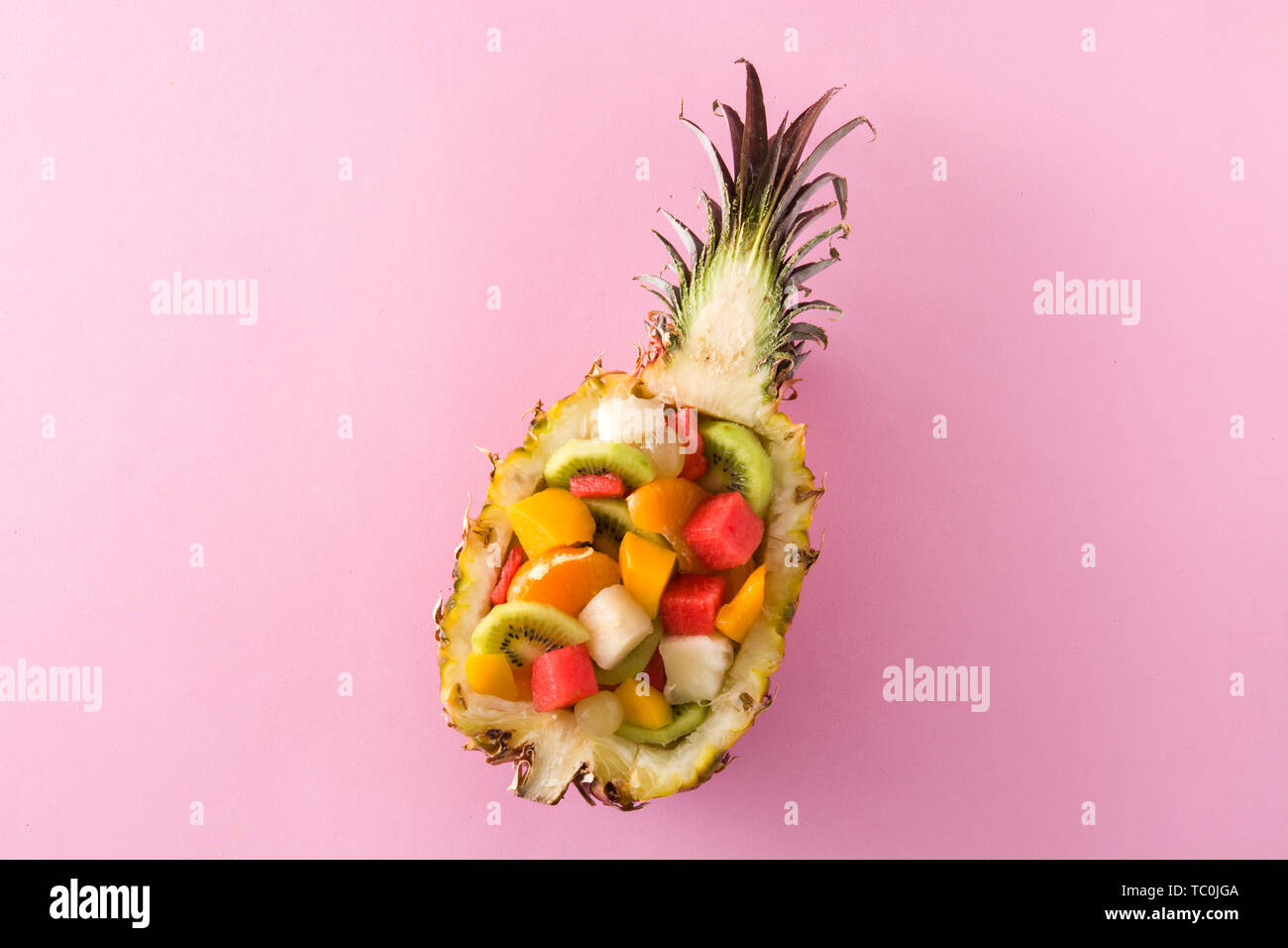 Mix fruit served inside pineapple on pink background Stock Photo - Alamy
