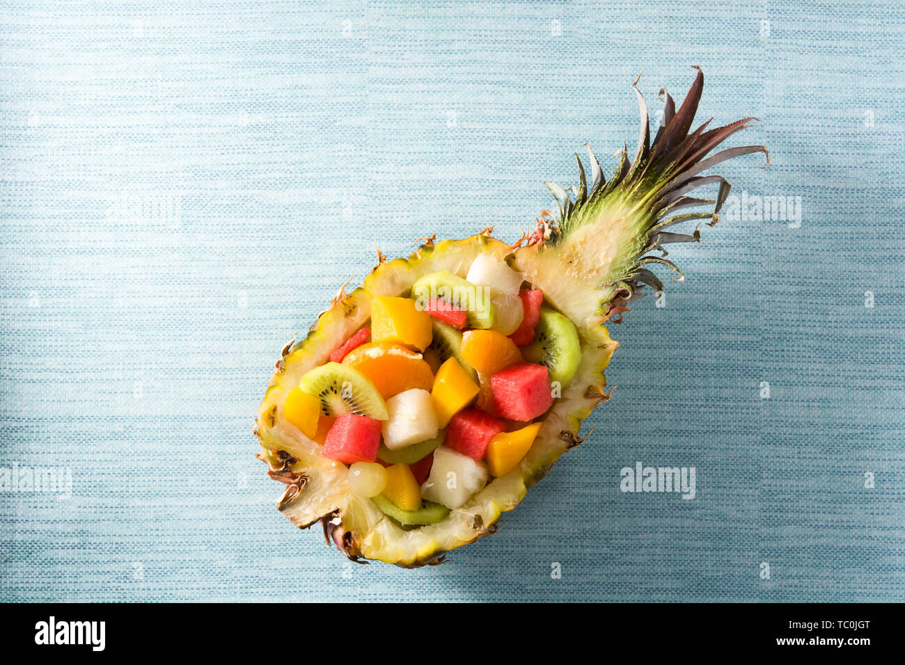 Mix fruit served inside pineapple on blue background Stock Photo - Alamy