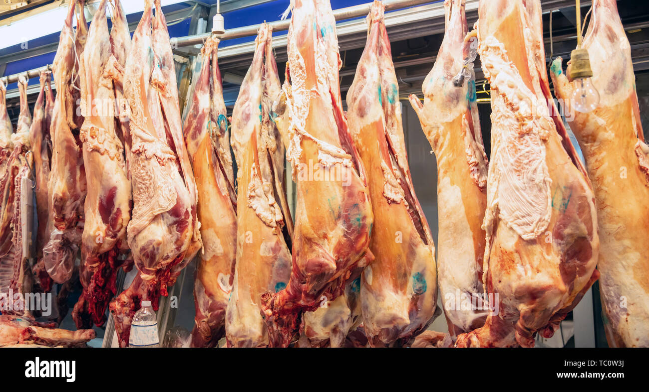 Meat market concept. Lamb, sheep hanged on hooks out of butcher shop ...
