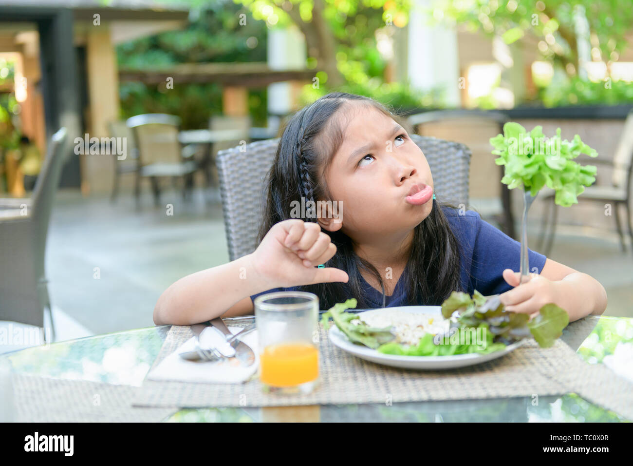 asian child girl with expression of disgust against vegetables in salad ...