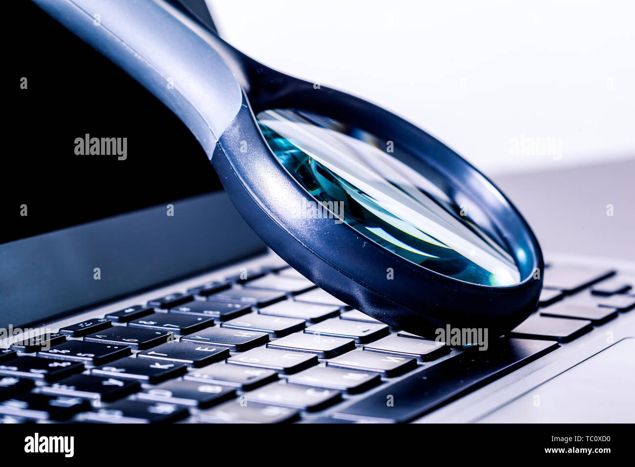 Closeup images of magnifying glass on laptop keyboard Stock Photo - Alamy