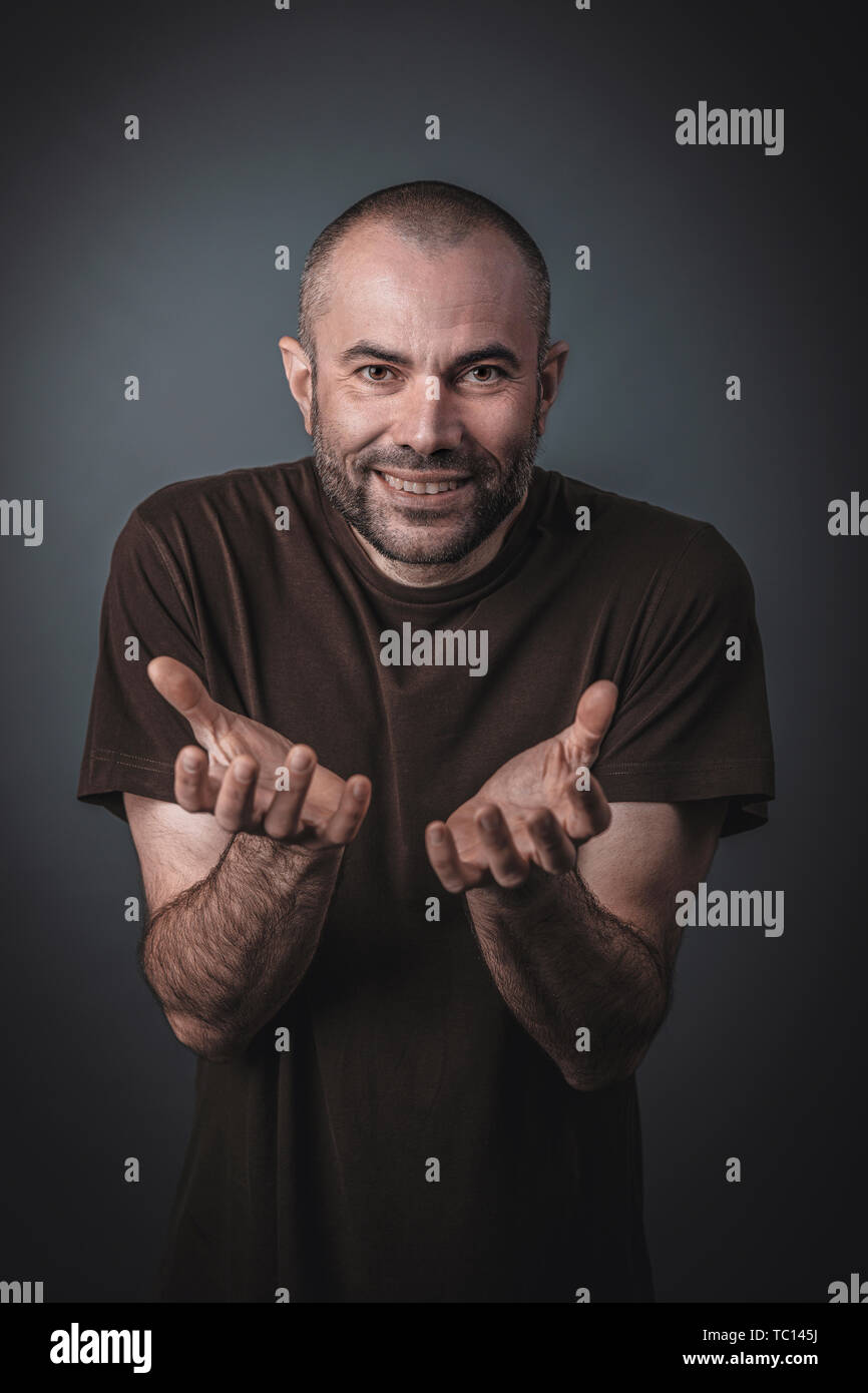 Portrait of a man with satisfied expression and clasped hands in front ...