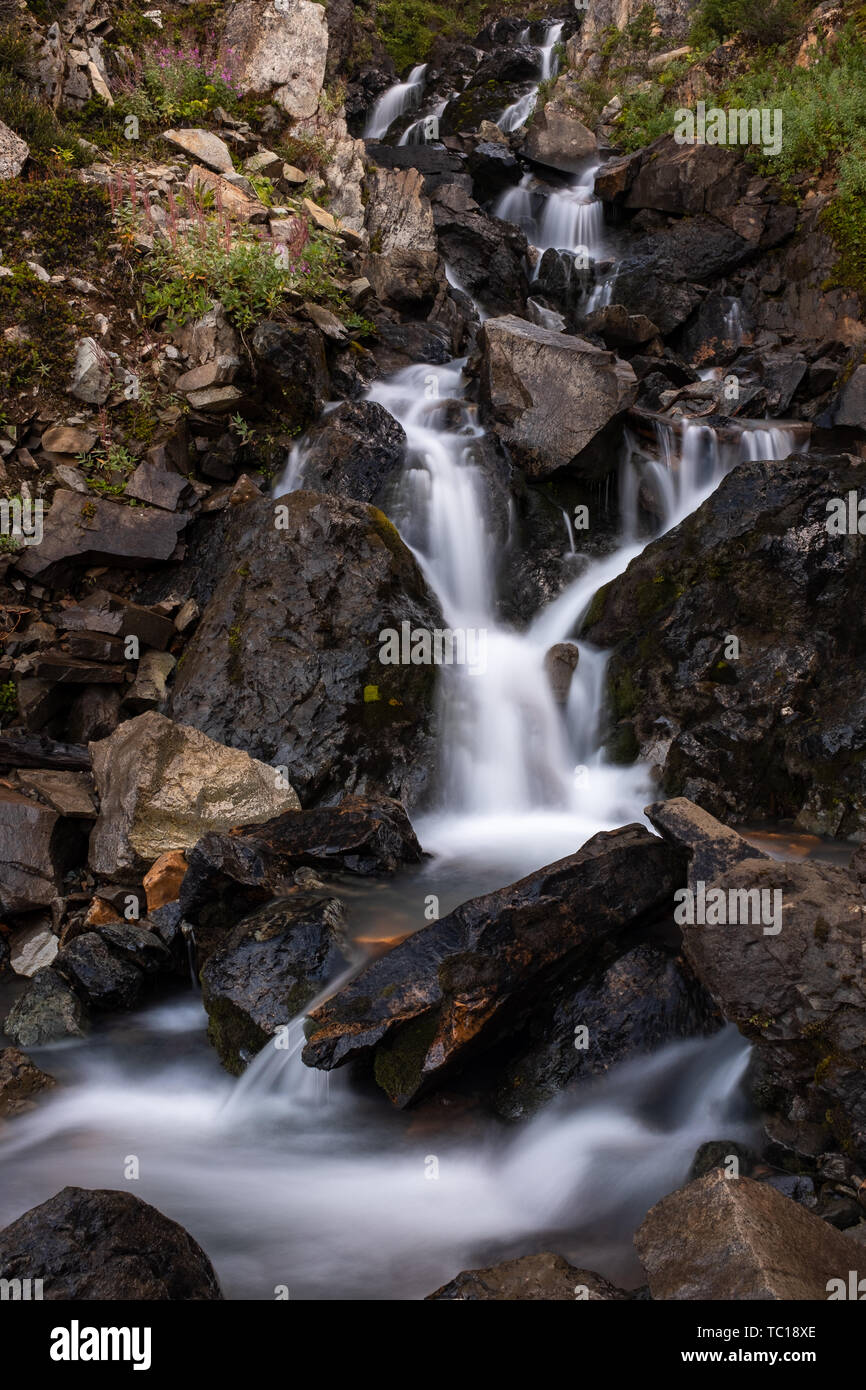 A close a small roadside waterfall as it tumbles on rocks on the dirt ...