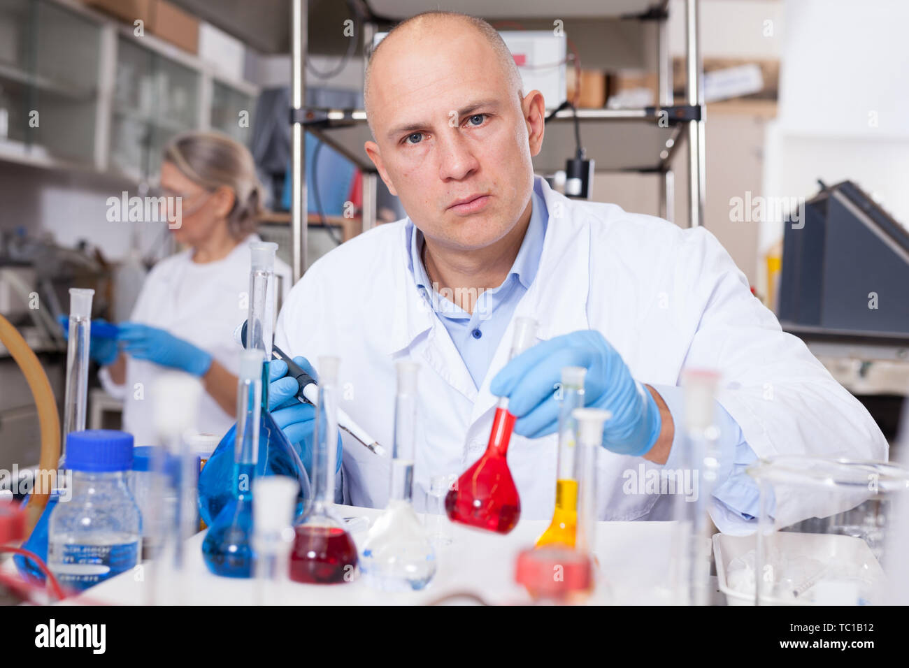 Professional biochemist performing experiments in lab room, mixing and ...