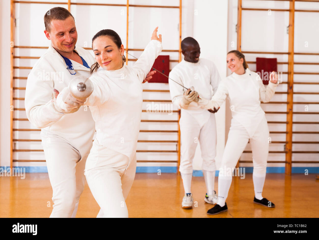 Female fencer practicing movements with trainer at fencing workout ...