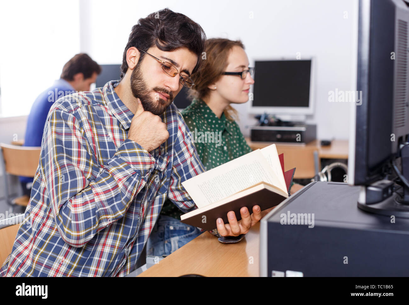 Intelligent man engaged in research working with computer and books in ...