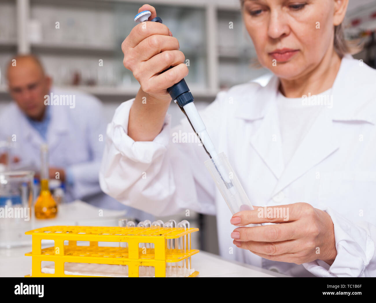 Closeup of hands of woman lab technician mixing reagents in test tube ...