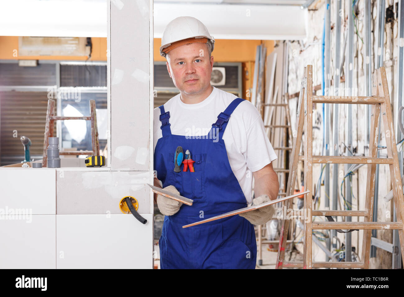 Focused construction worker engaged in wall tiling work during ...
