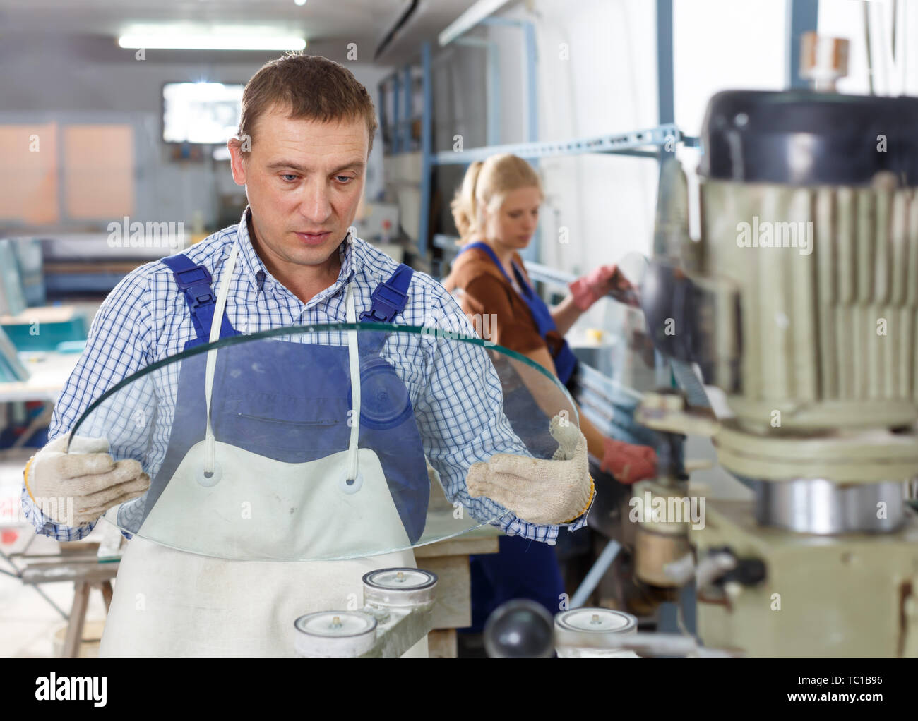 Experienced male worker of glass factory engaged in processing of ...