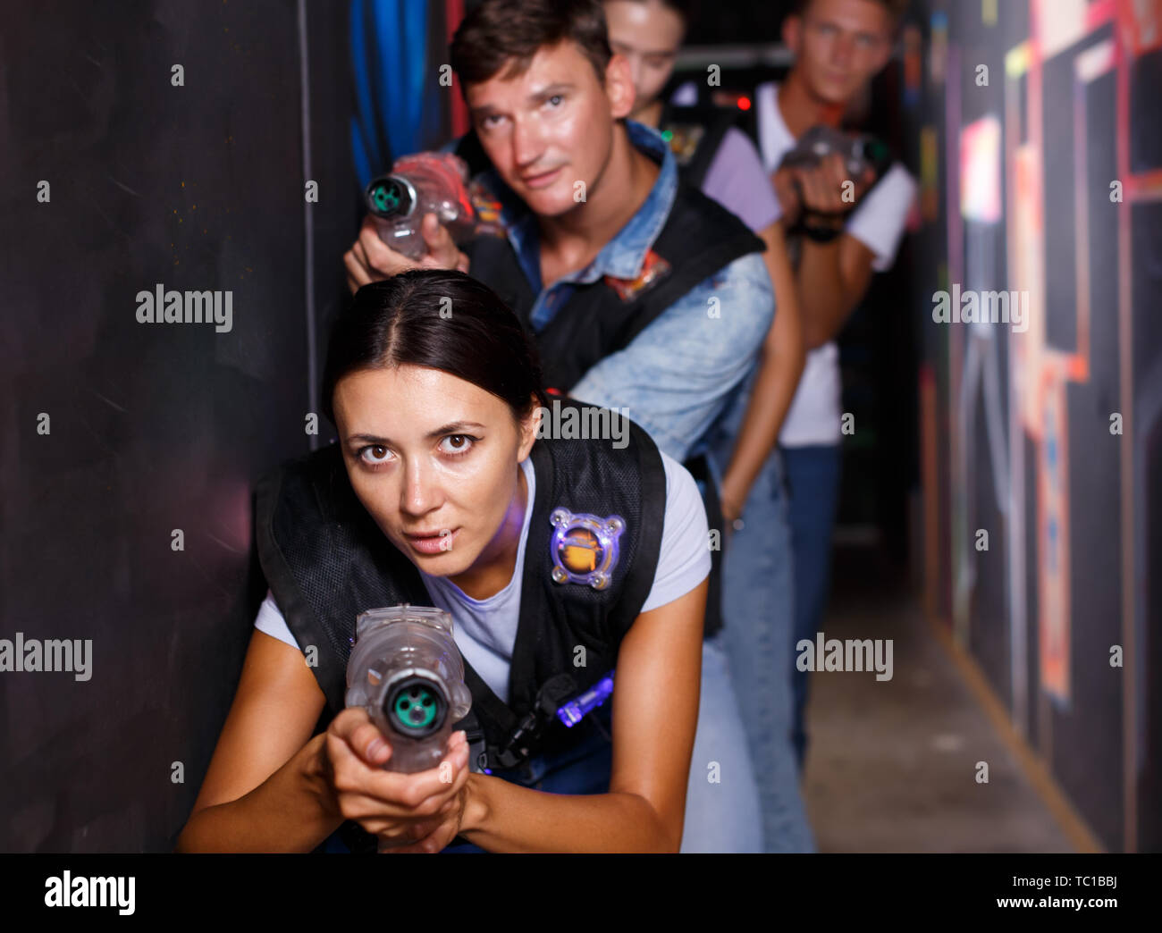 Group happy emotional people with laser guns playing laser tag game ...
