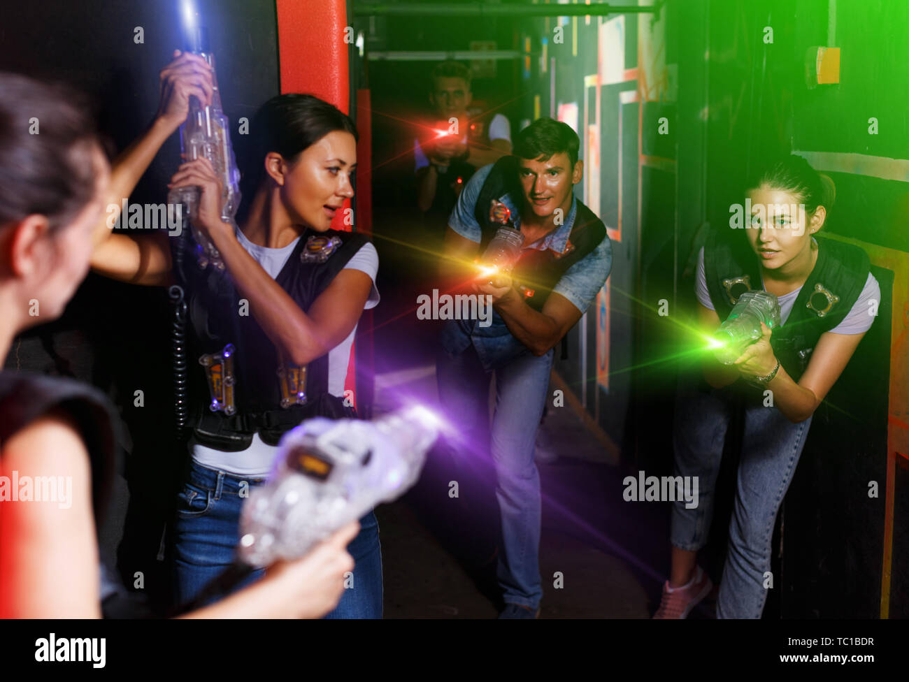Portrait of active young friends standing with laser guns during laser ...