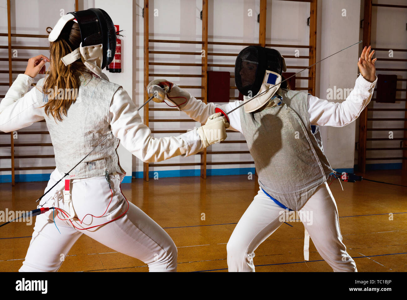 Two positive smiling female fencers exercising movements in duel at ...