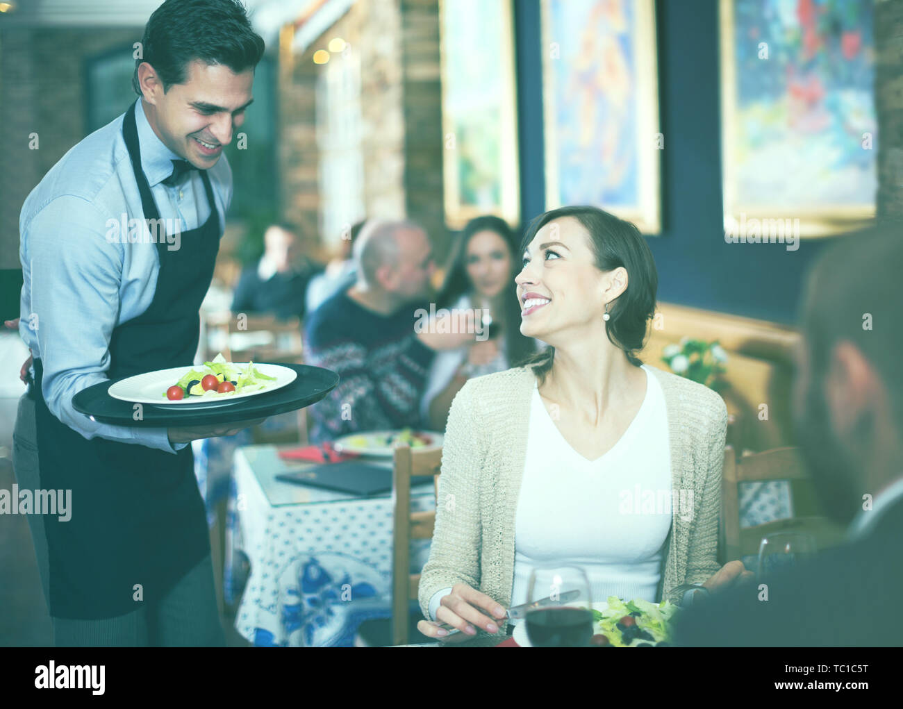 professional smiling waiter man serving company of positive guests at ...
