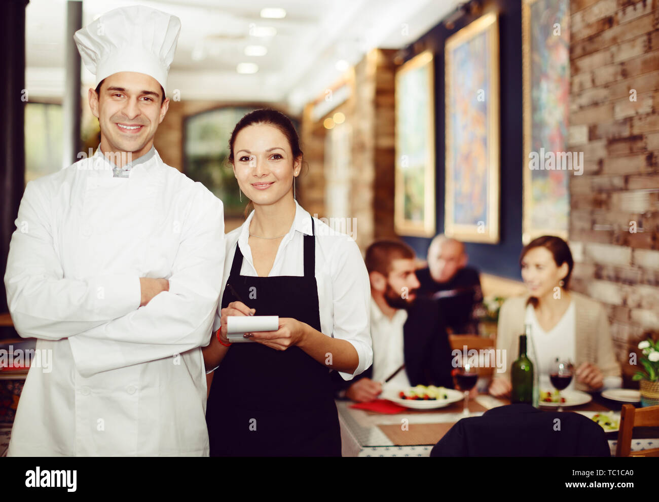 Portrait of smiling waitress with professional chef at a restaurant ...