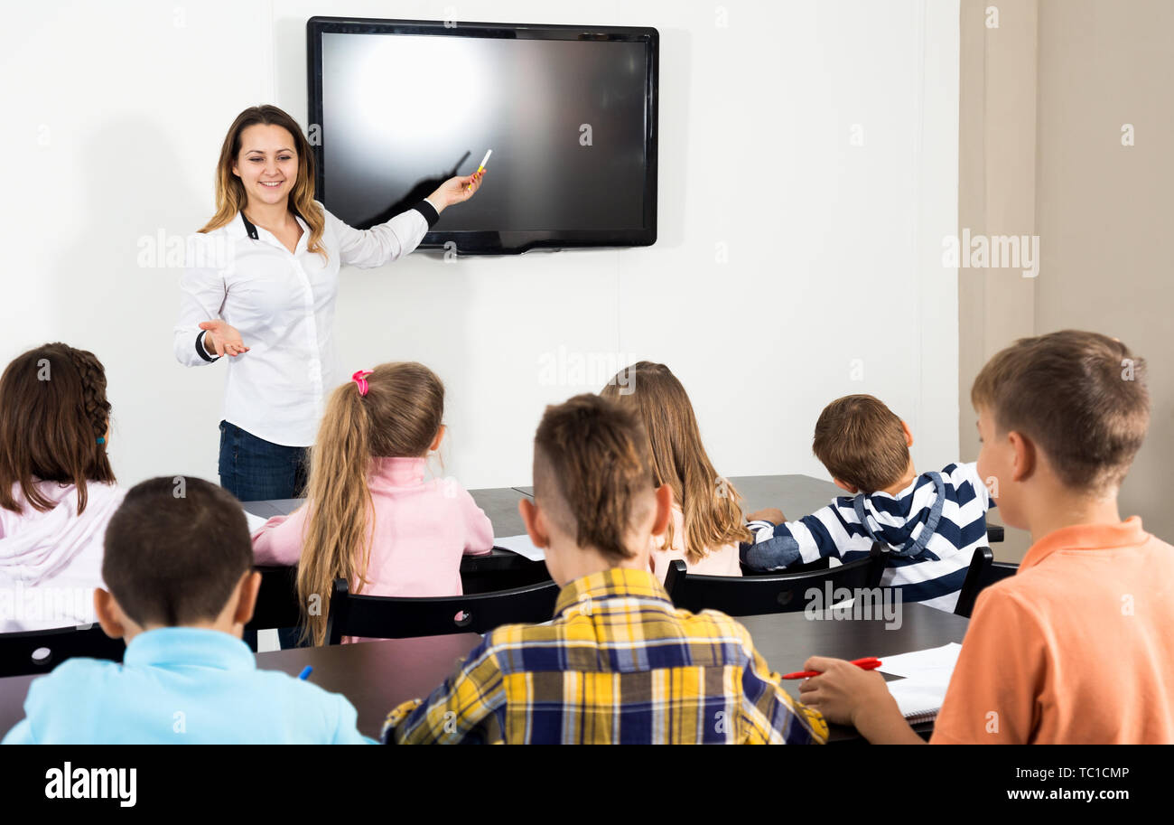 Cheerful female professor and elementary age children at classroom ...