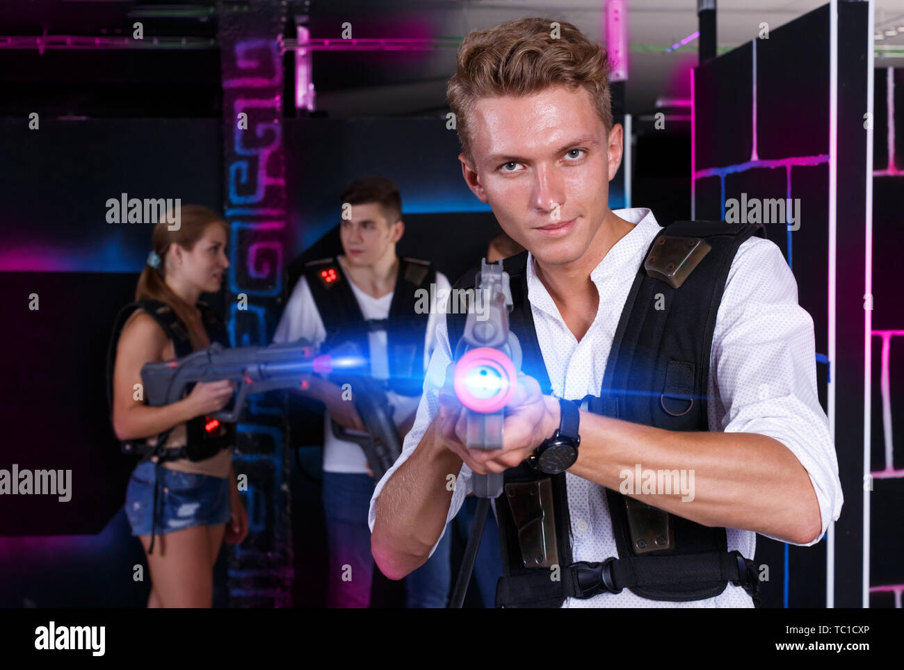 Portrait of guy holding laser pistol while playing lasertag with ...