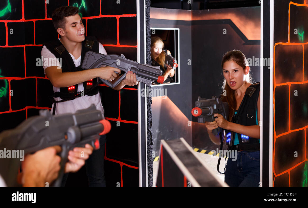 portrait of excited positive people playing enthusiastically laser tag ...