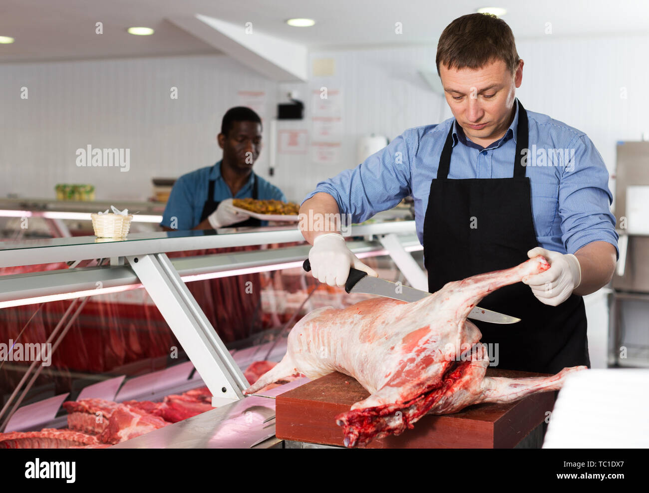 Professional male butcher cutting lamb carcass in butcher shop Stock ...