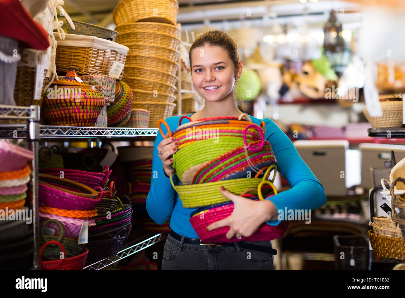 girl customer standing with multicolor wicker basket in decor items ...