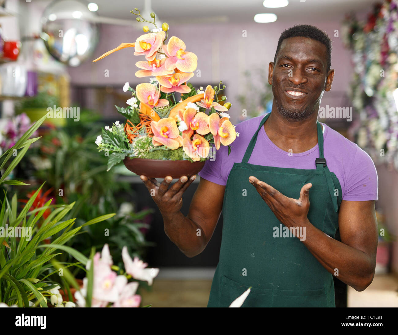 Friendly African man owner of floral shop offering compositions with ...