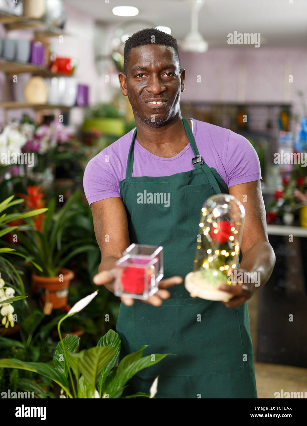 Friendly African man owner of floral shop offering compositions with ...