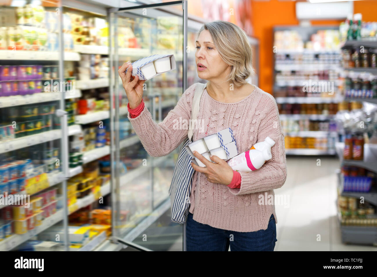 Female reading product label while choosing groceries in supermarket ...