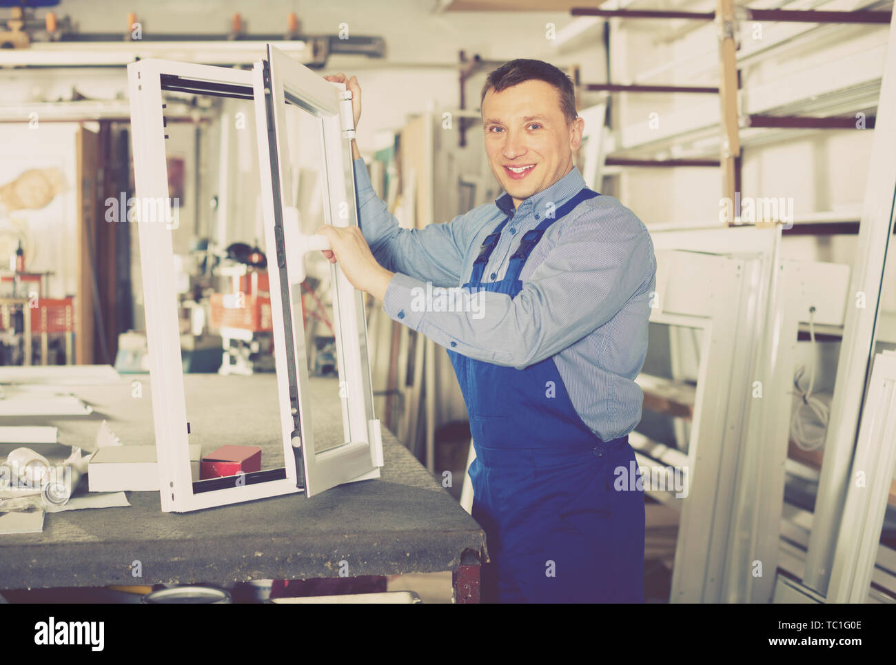 Guy worker is demonstrating the window frame in workshop Stock Photo ...