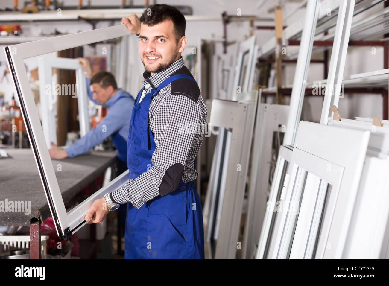 Young man worker is demonstrating PVC manufacturing output in workshop ...