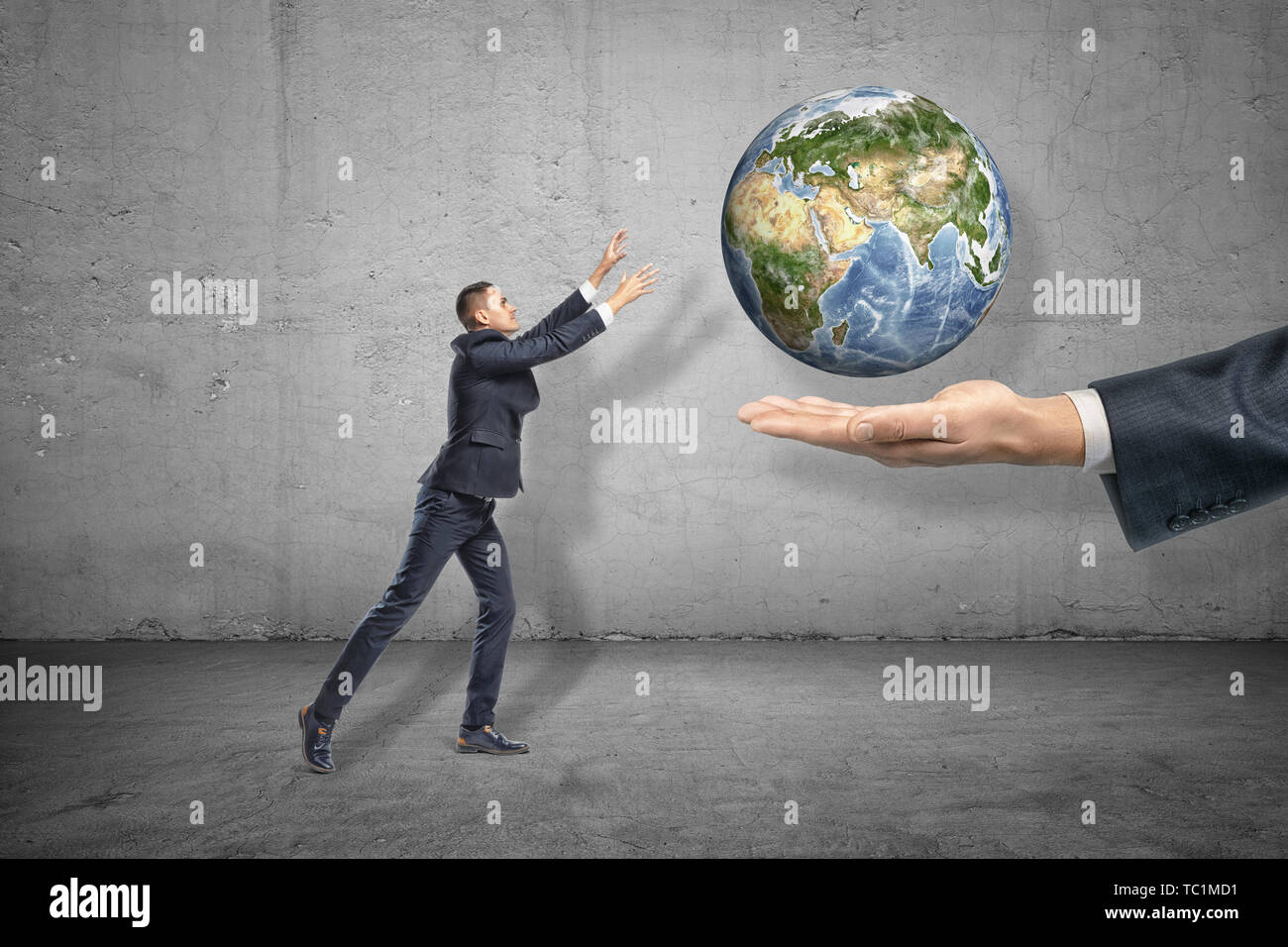 Side view of little businessman reaching out for planet Earth that is ...