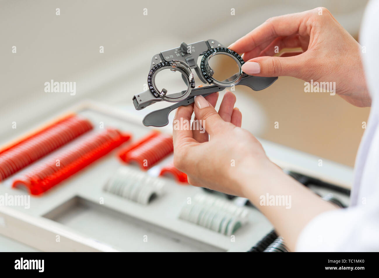 Selecting size. Ophthalmologist in white robe holding unusual glasses ...