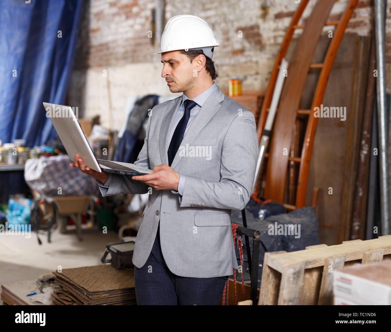 Confident male architect in suit and helmet controlling process of ...