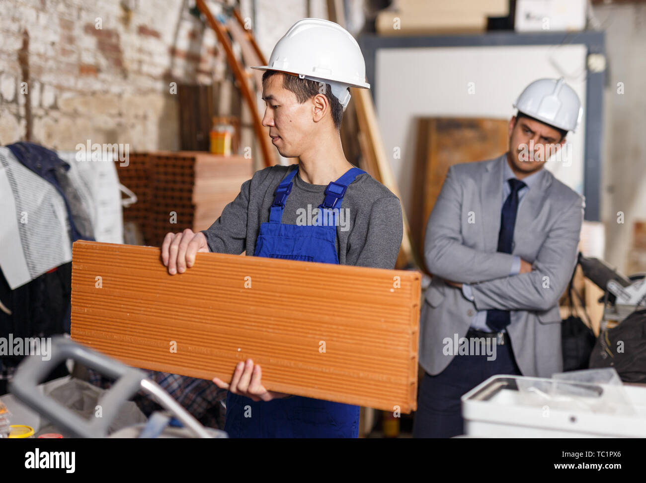 Strict male chief supervising quality of work of employee at building ...