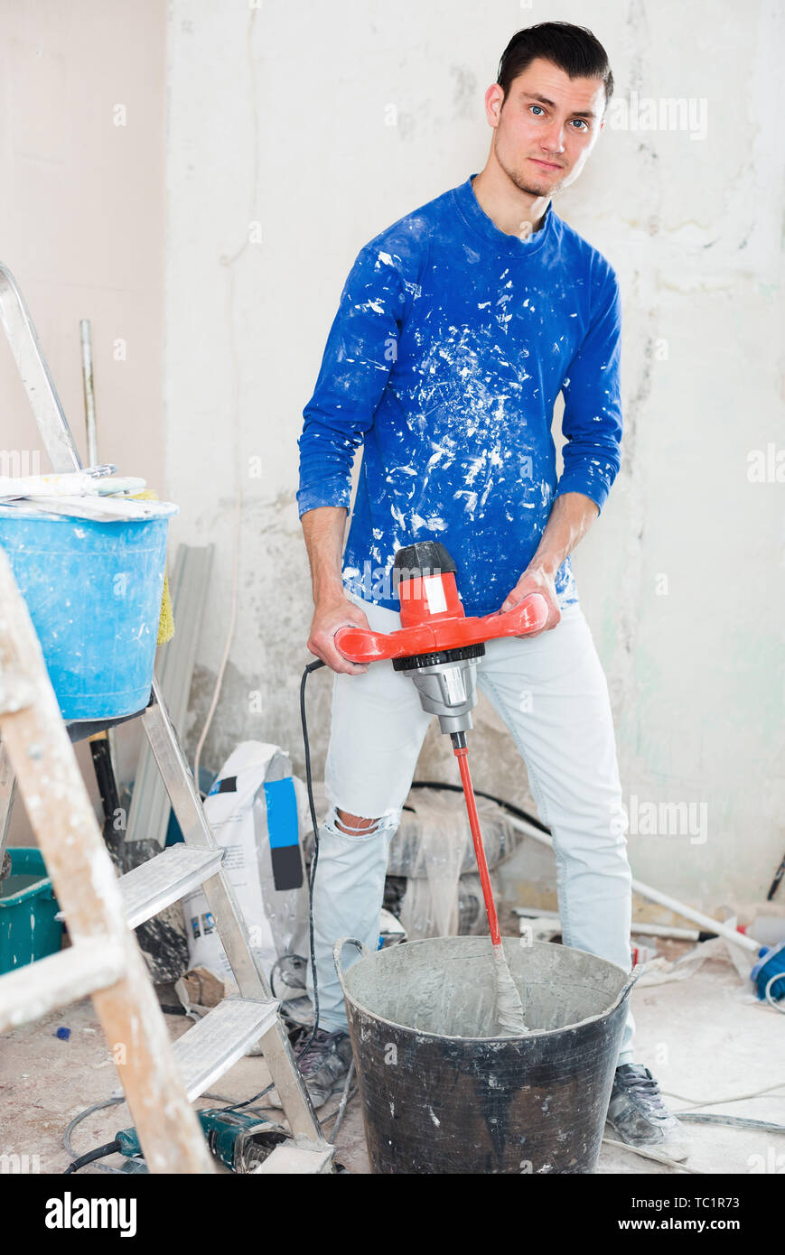 Male builder mixing plaster in bucket using electric mixer Stock Photo ...