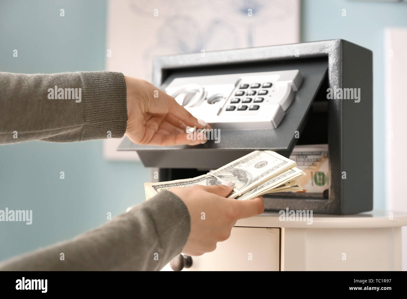 Woman putting money in safe at home Stock Photo - Alamy