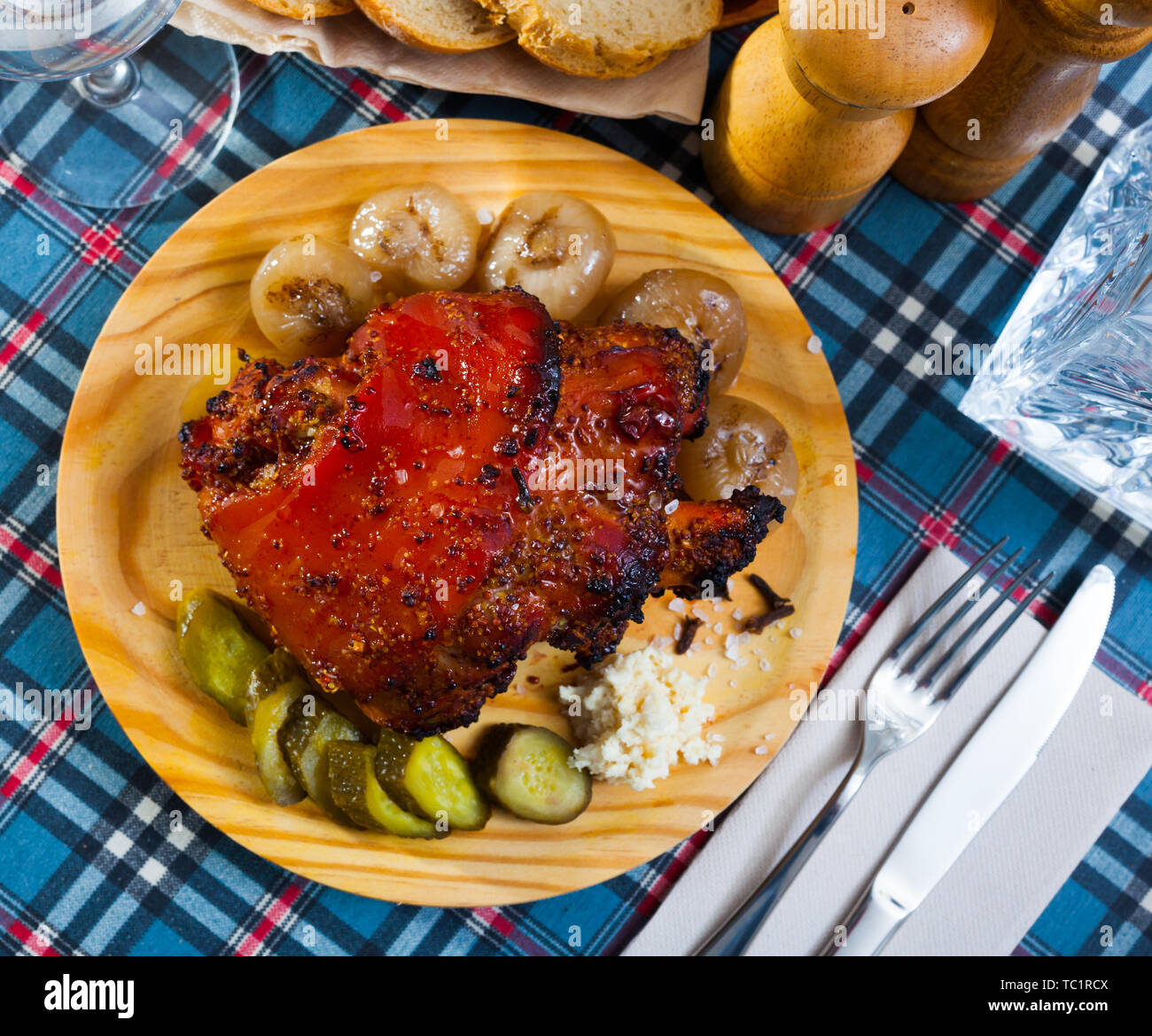 Appetizing pork knuckle served with boiled onions and pickled cucumbers ...