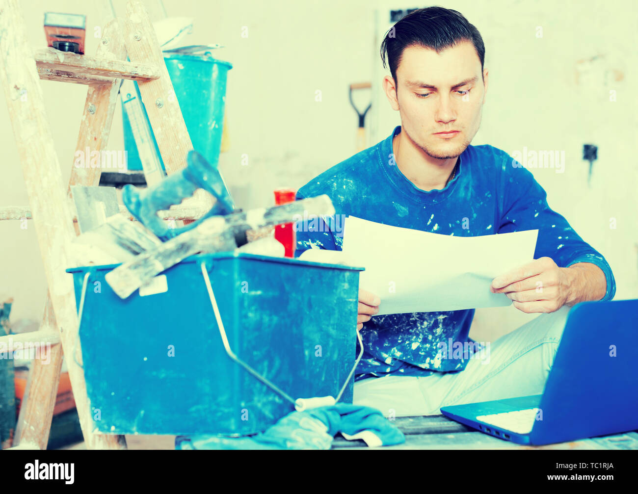 Serious builder handyman checking plan of house renovation on papers ...