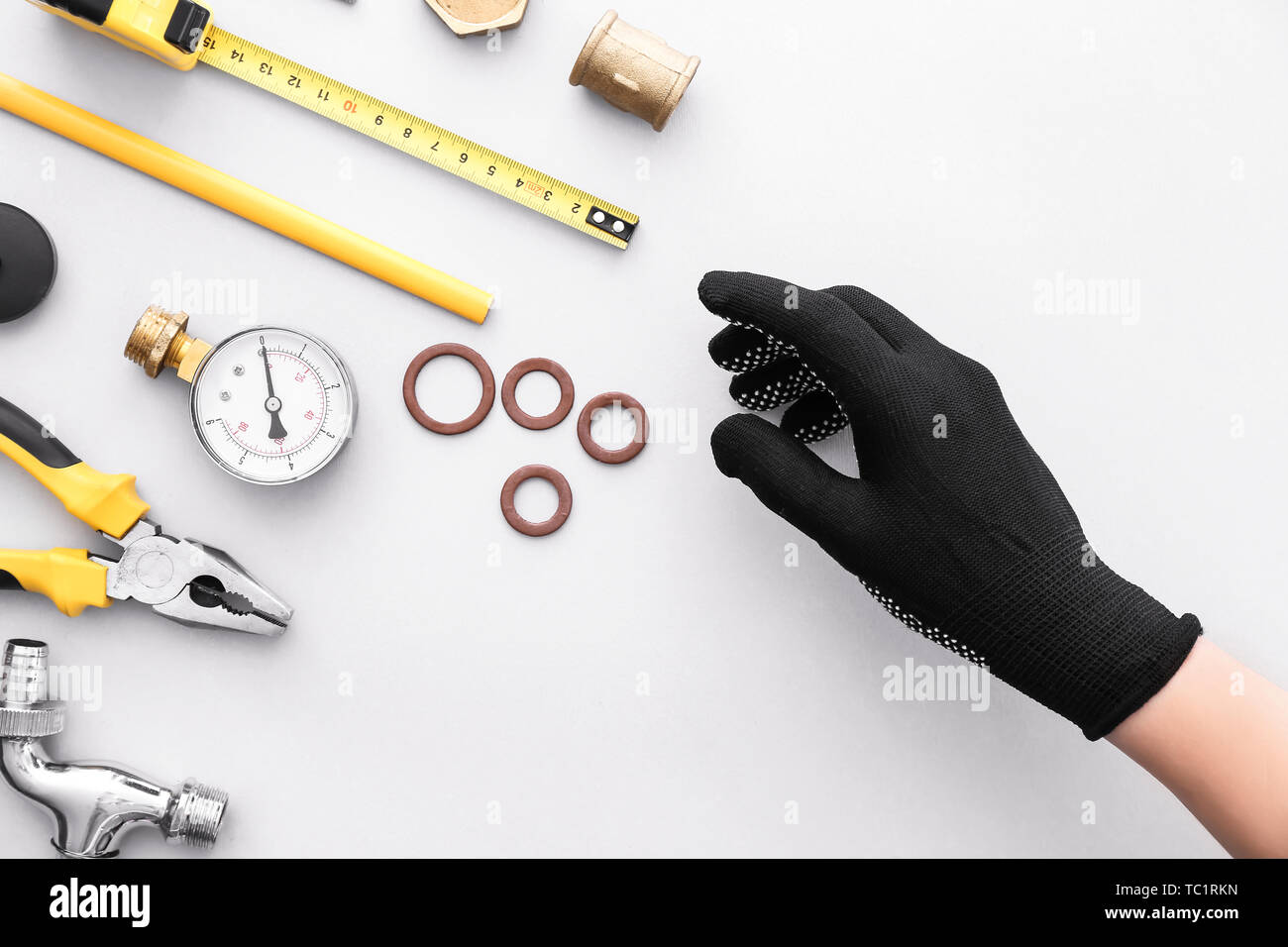 Plumber's hand and set of tools on white background Stock Photo - Alamy