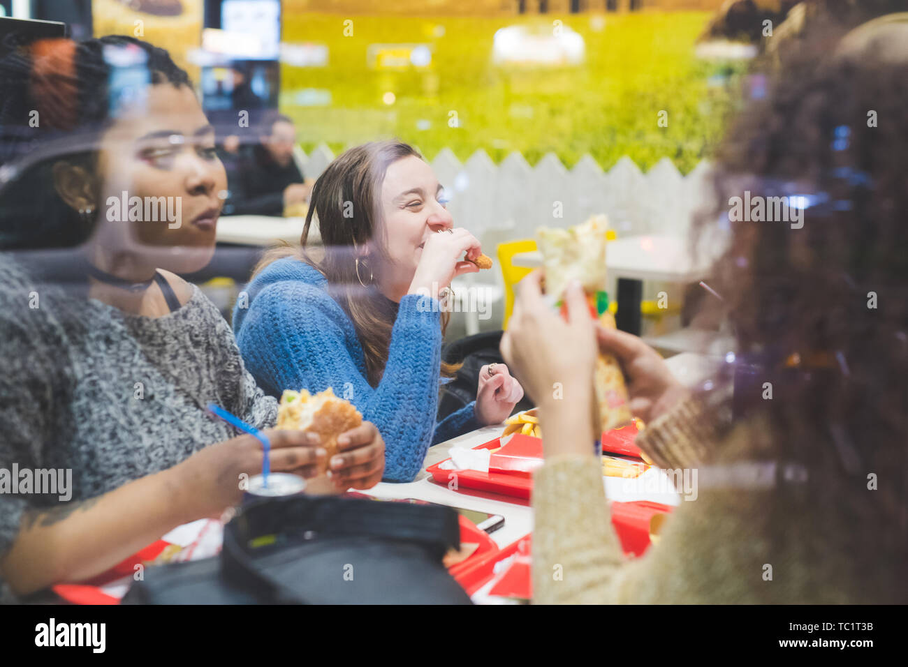 group of young women eating together in fast food– friendship, new ...