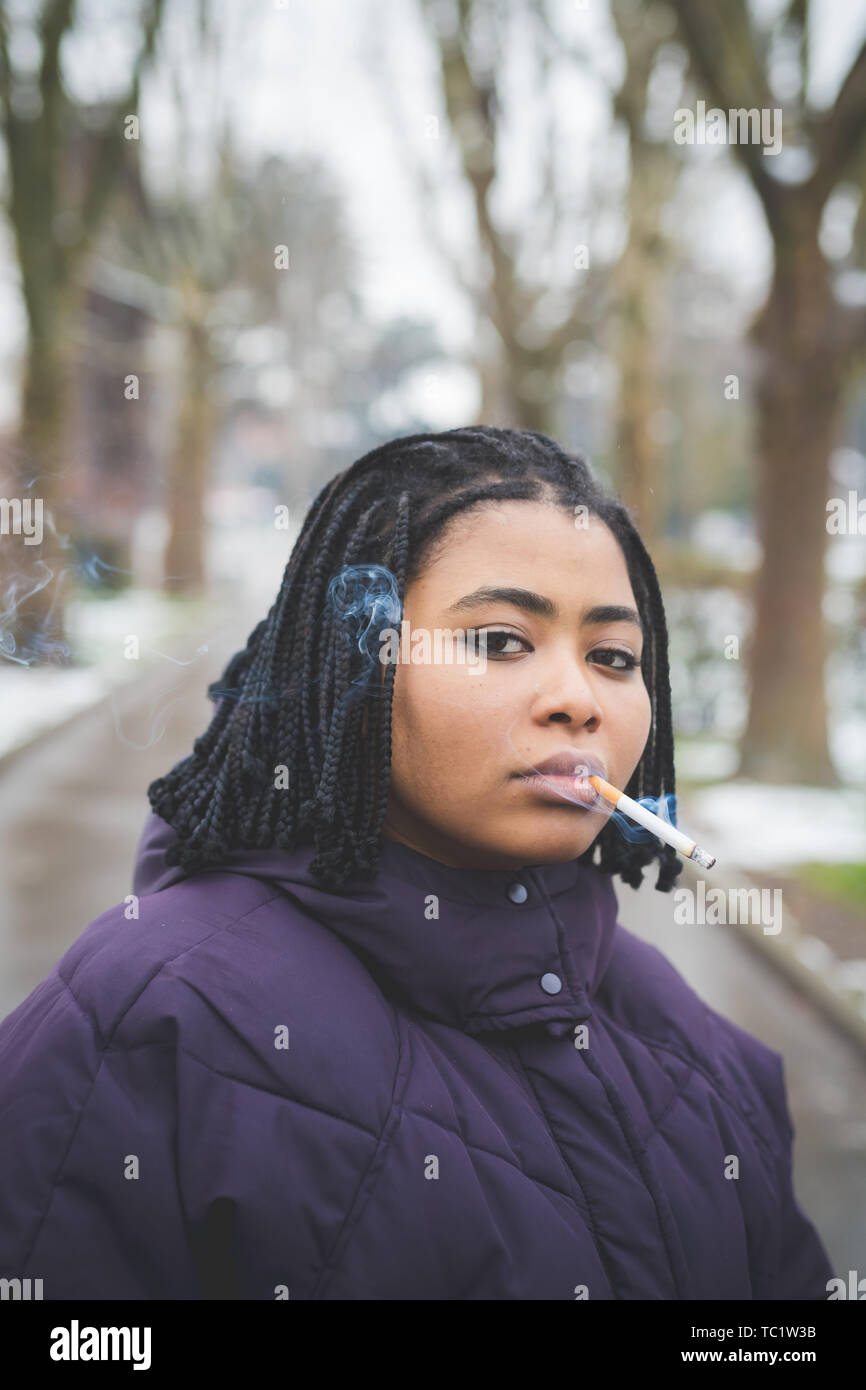 portrait of young african woman smoking cigarette and looking camera ...