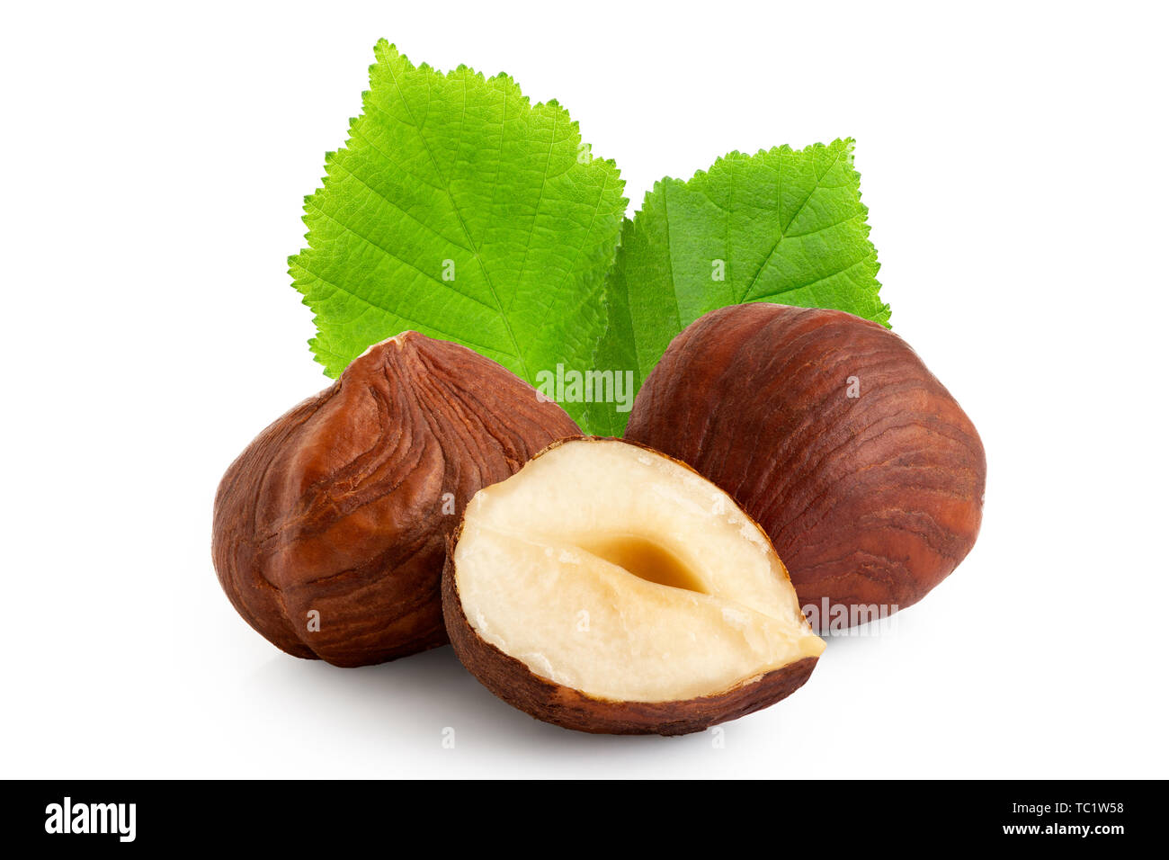 Two and half hazelnuts with skin and green leaves isolated on white ...