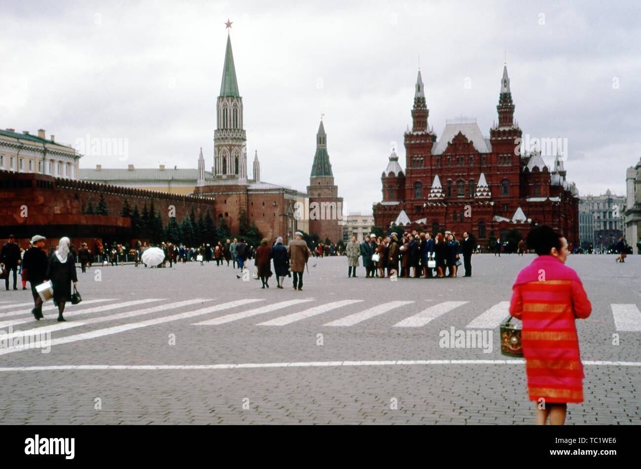 A woman in a bright coat walks among the crowds in Red Square near the ...