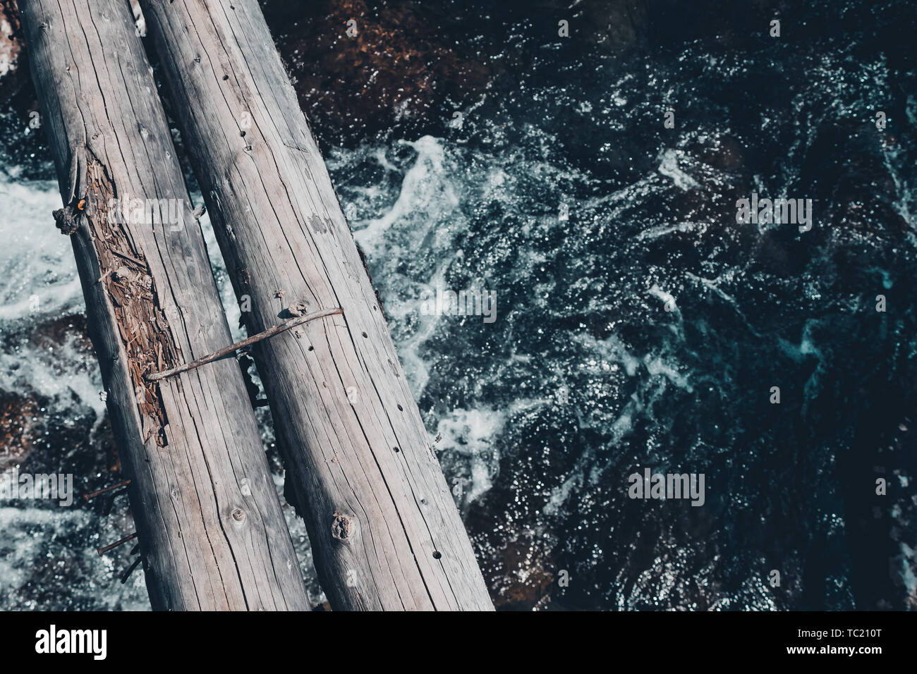 Old wooden tourist bridge made of woods and ropes across mountain river ...