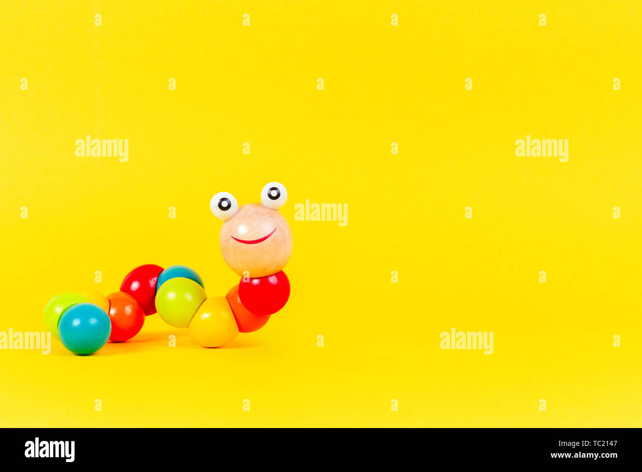 Colorful wooden baby toy worm on yellow background Stock Photo - Alamy