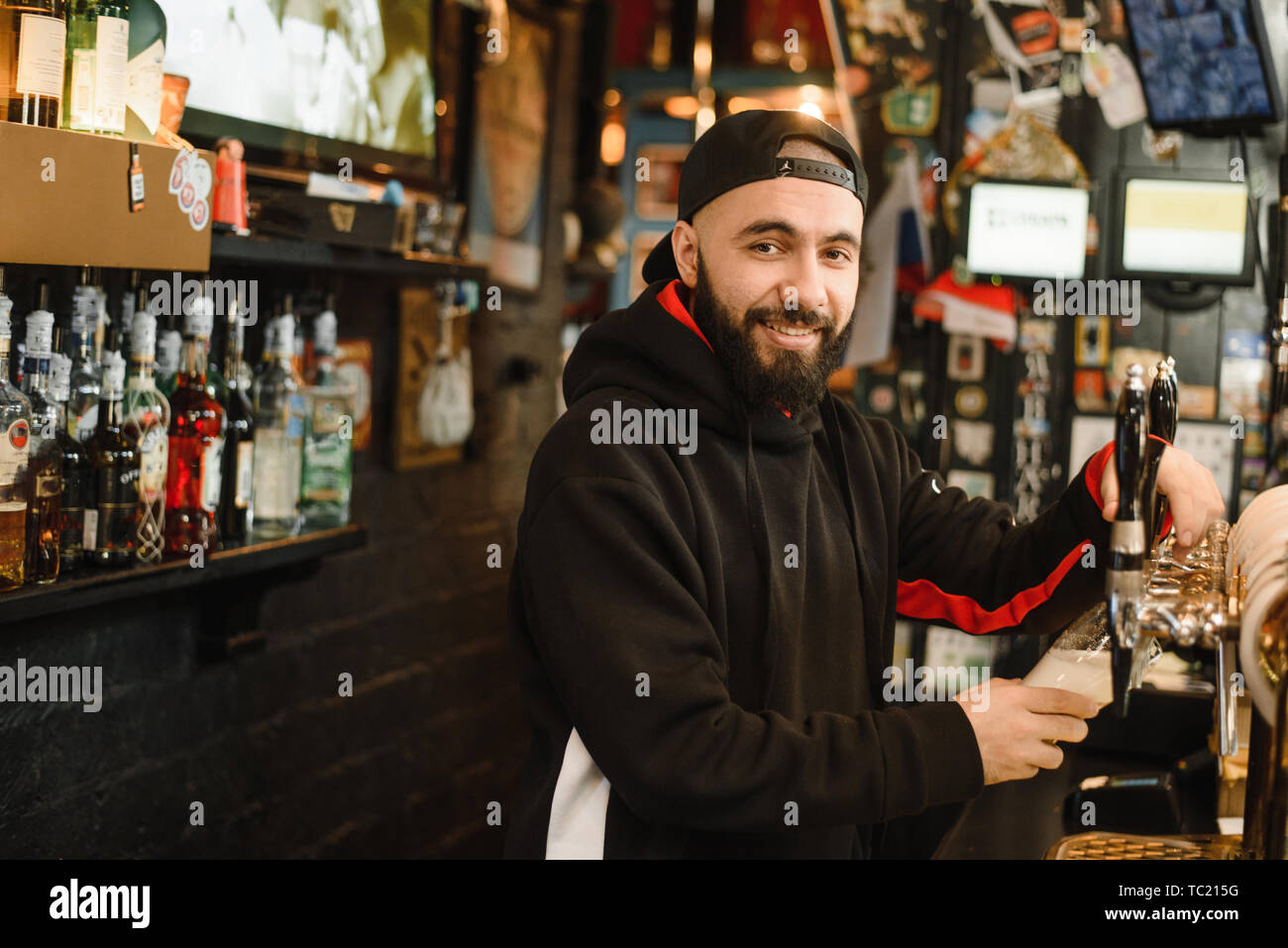 smiling barman pouring beer in a bar. Bearded courageous man pours you ...