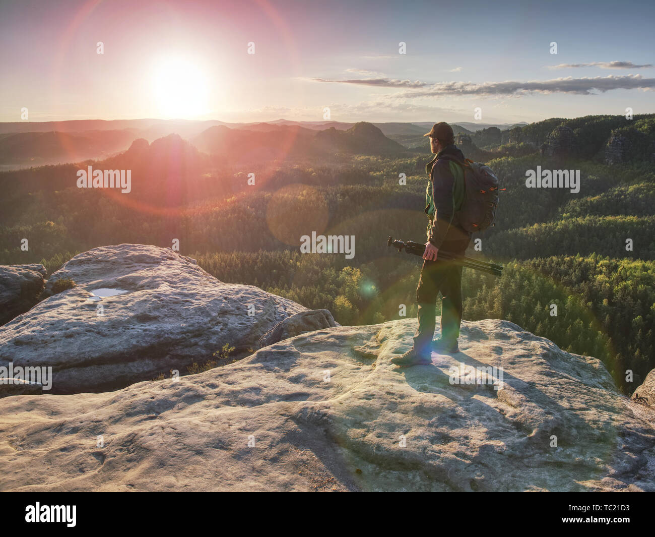 Photographer on mountain cliff above valley with morning mist hold ...