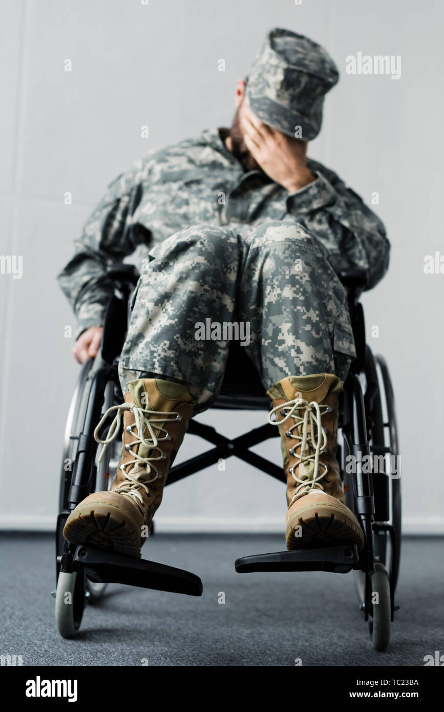 selective focus of disabled military man in uniform sitting in ...
