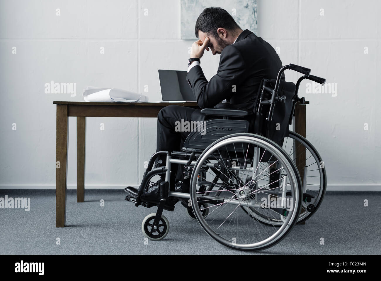 depressed disabled businessman sitting in wheelchair at workplace with ...