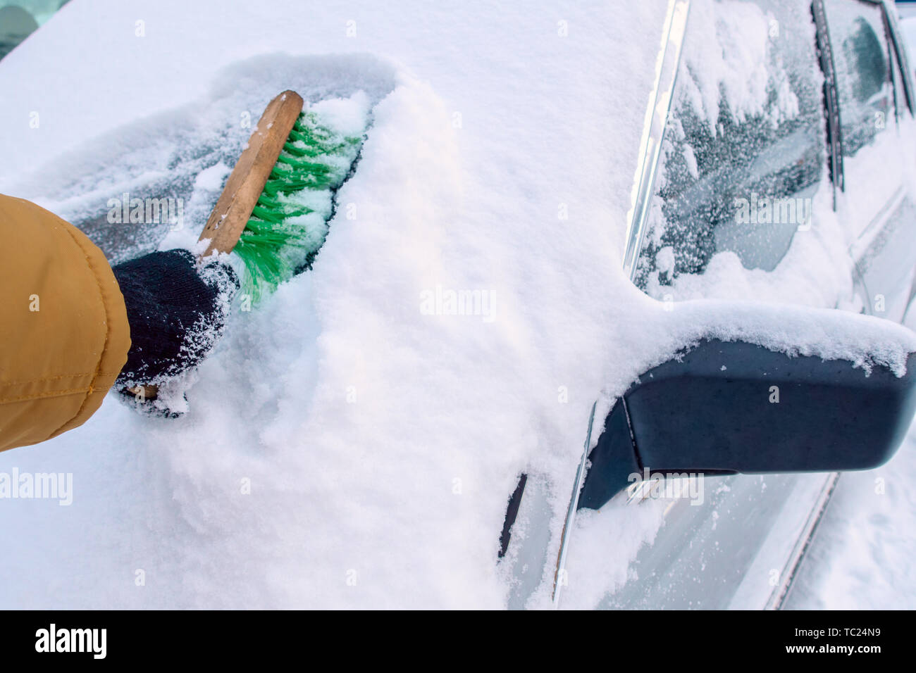 snow on cars. blizzard bombarded transport. man cleans the windshield ...