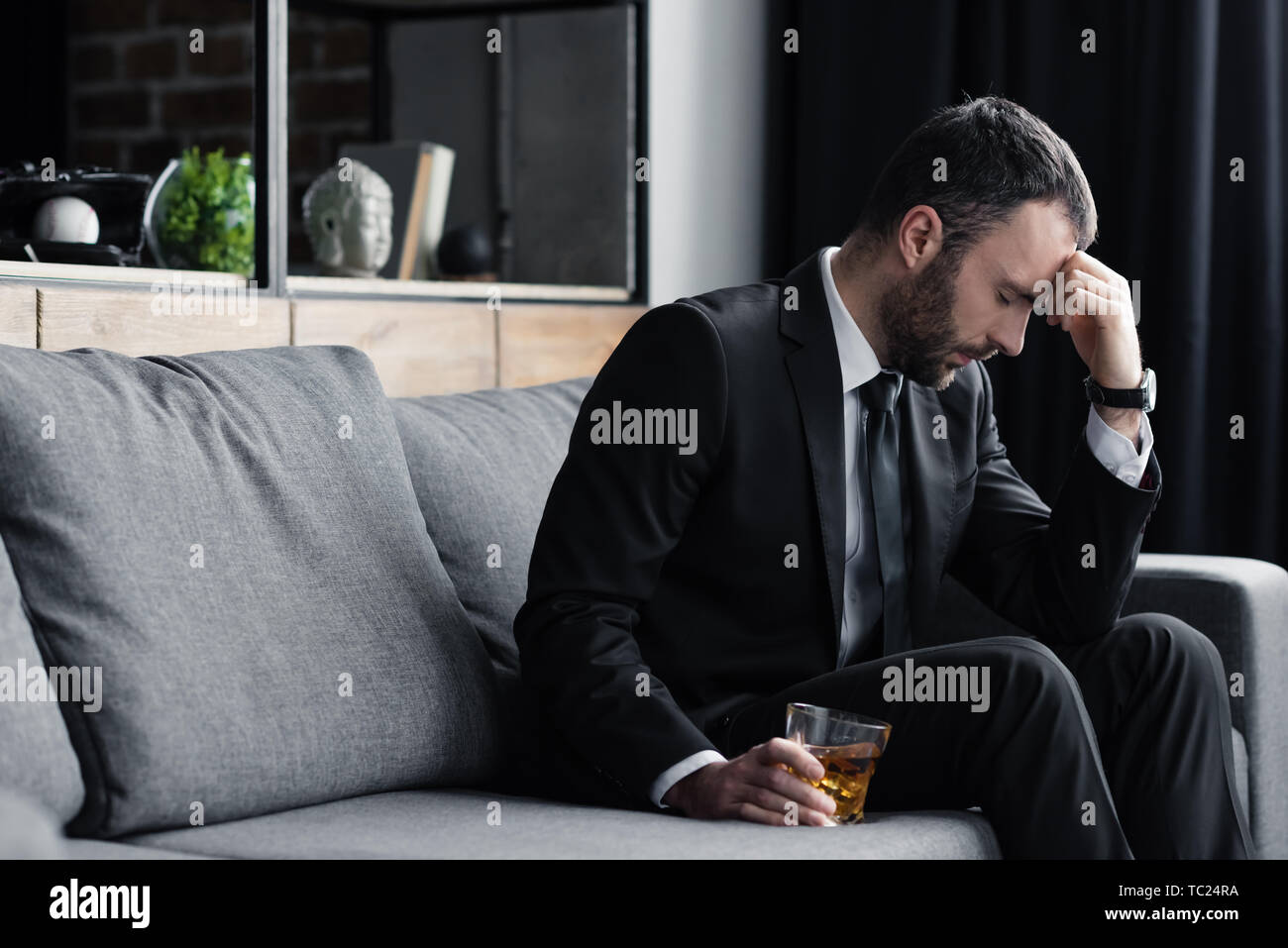 frustrated man in suit sitting on sofa with closed eyes and holding ...